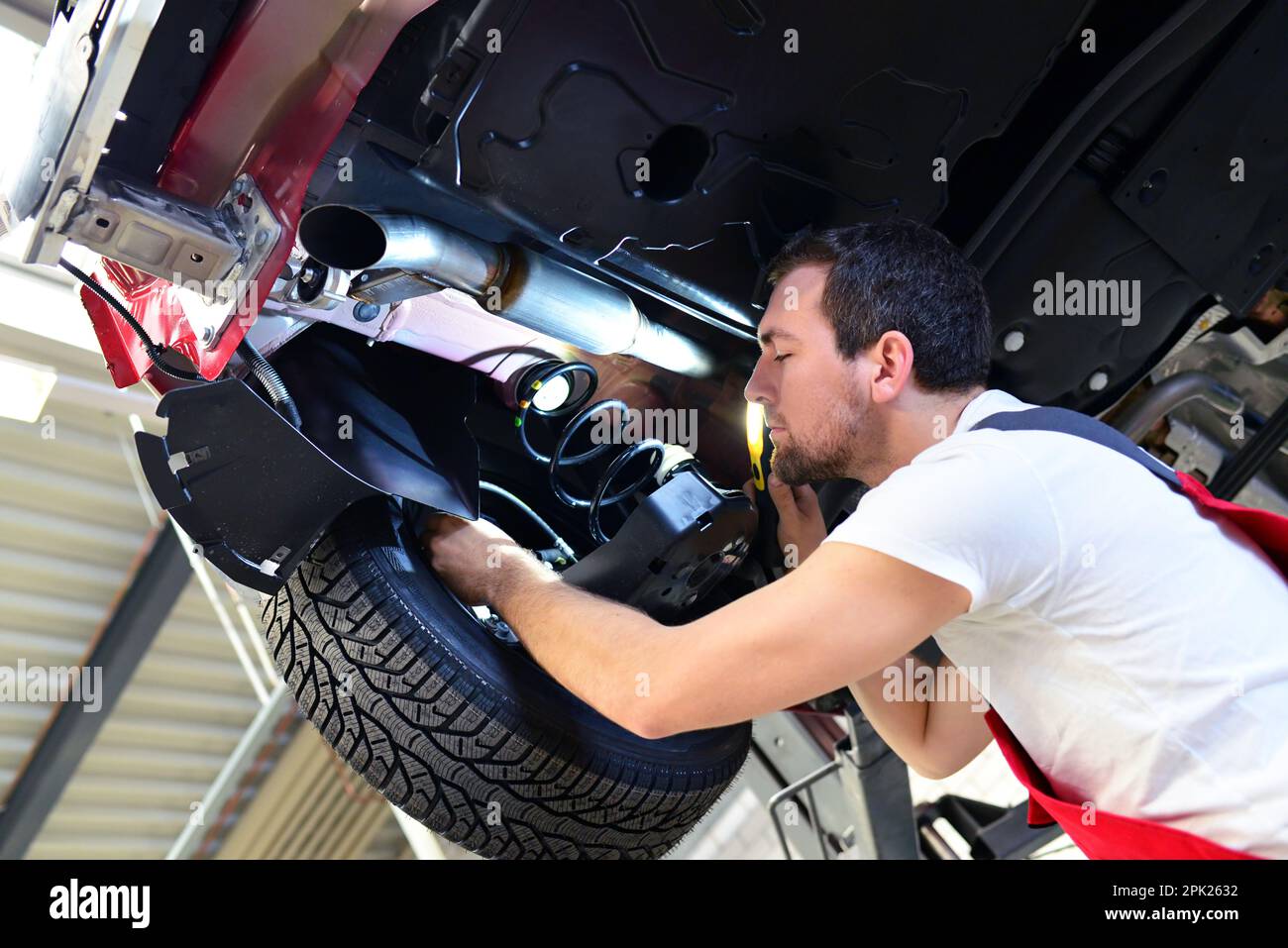 professional car mechanic works in a workshop and repairs vehicles ...