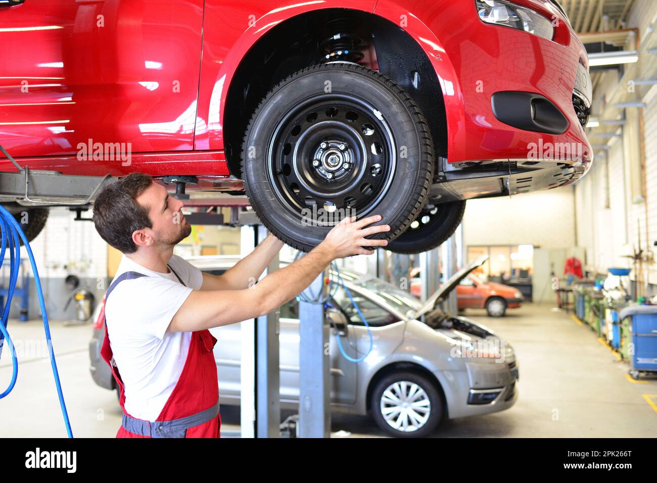 professional car mechanic works in a workshop and repairs vehicles ...