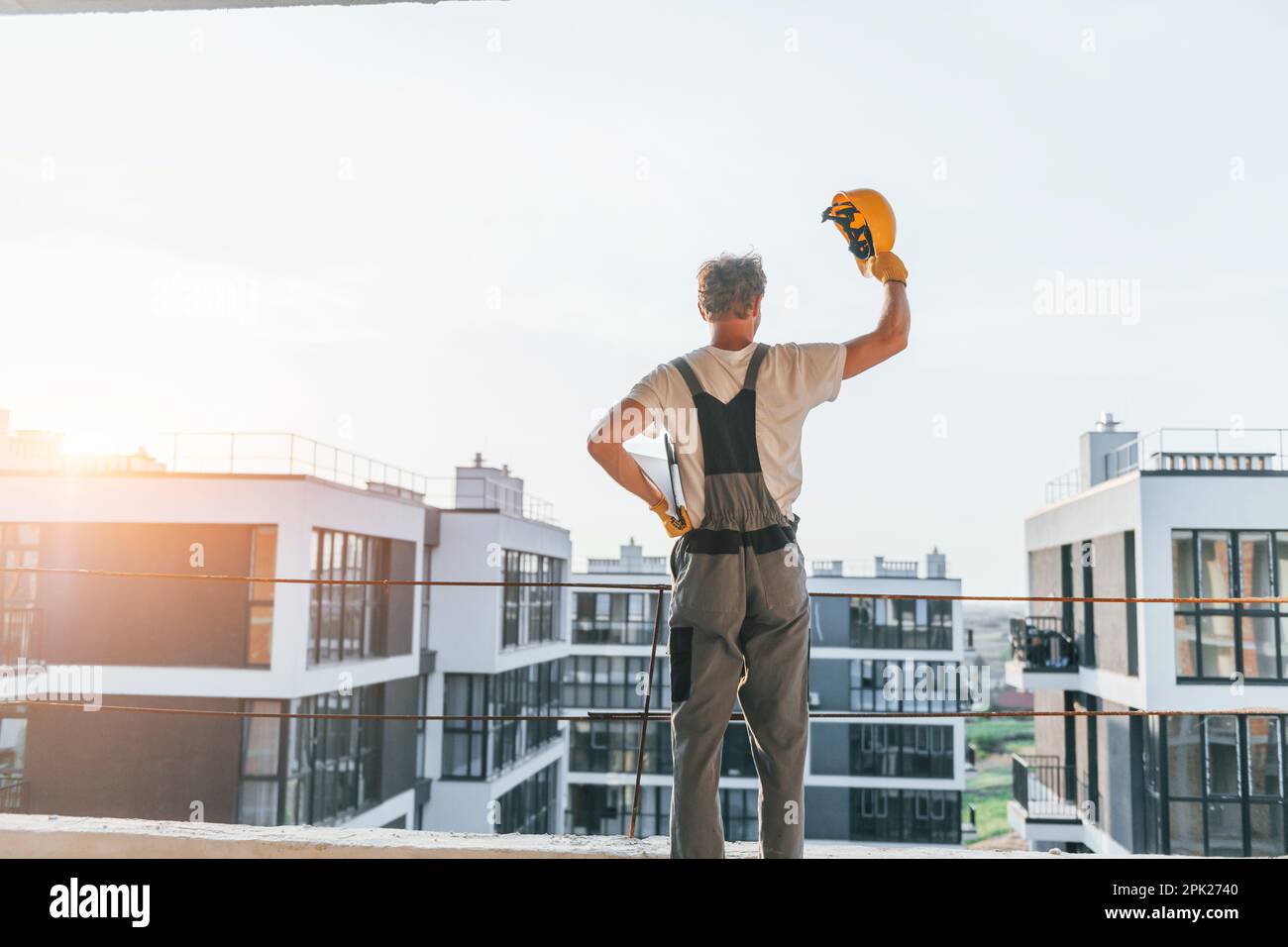 Illuminated by sunlight. Young man working in uniform at construction ...