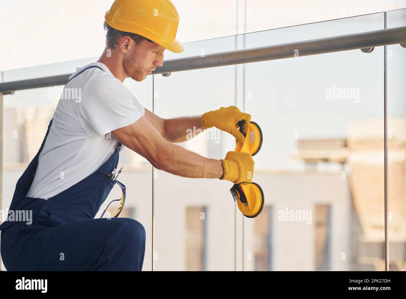 Using tool. Young man working in uniform at construction at daytime ...