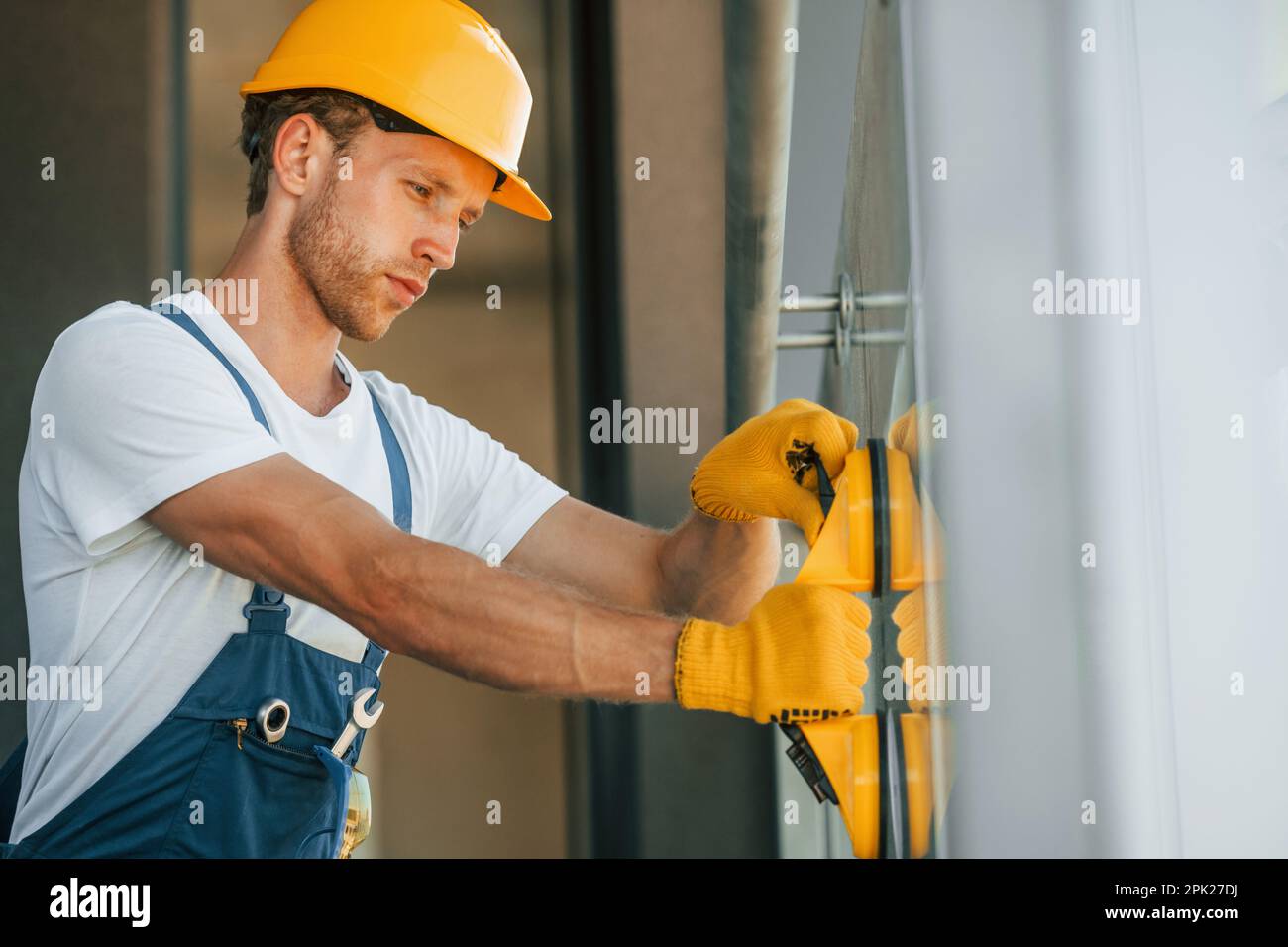 Side view. Young man working in uniform at construction at daytime ...