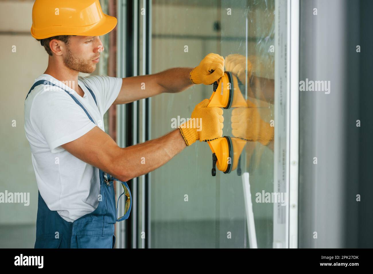 Side view. Young man working in uniform at construction at daytime ...