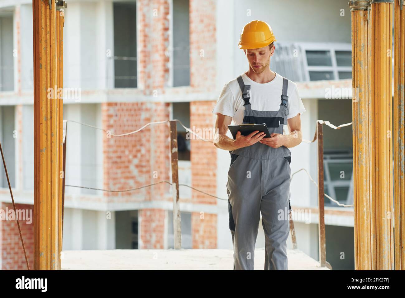 Indoors in the room. Young man working in uniform at construction at ...