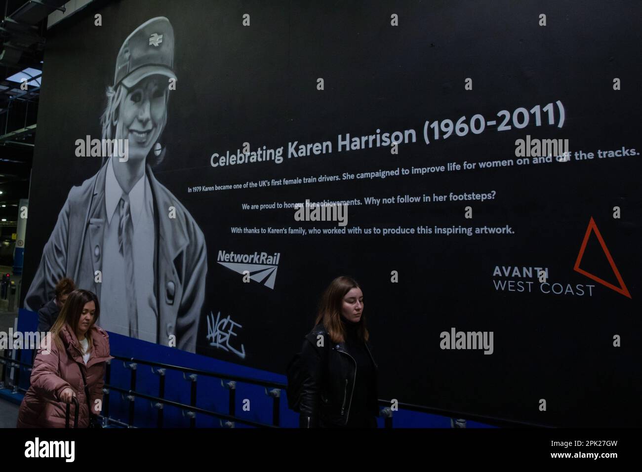 London, UK. 8th March, 2023. Rail passengers pass a mural of Karen ...