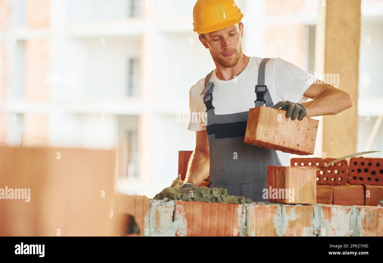 Building process. Young man working in uniform at construction at ...