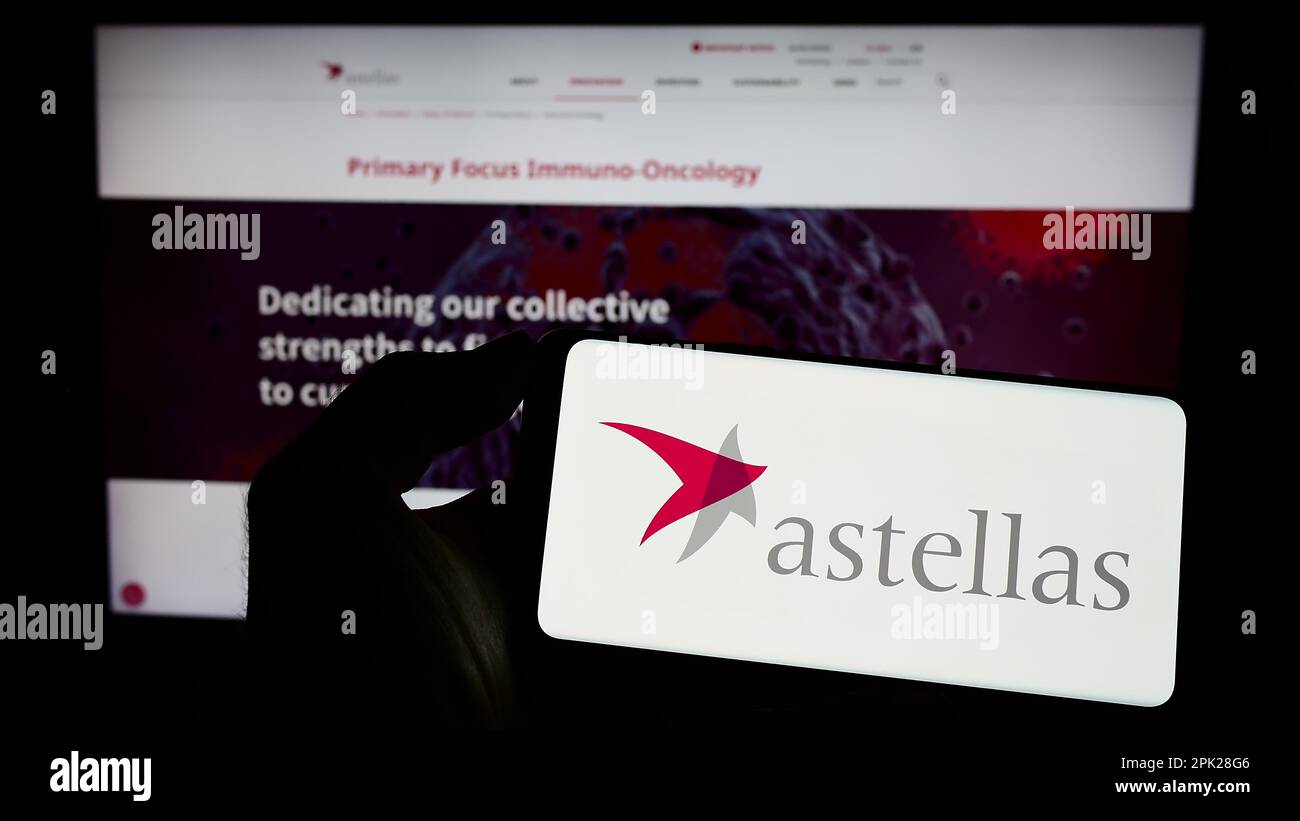 Person holding smartphone with logo of pharmaceutical company Astellas Pharma Inc. on screen in ...