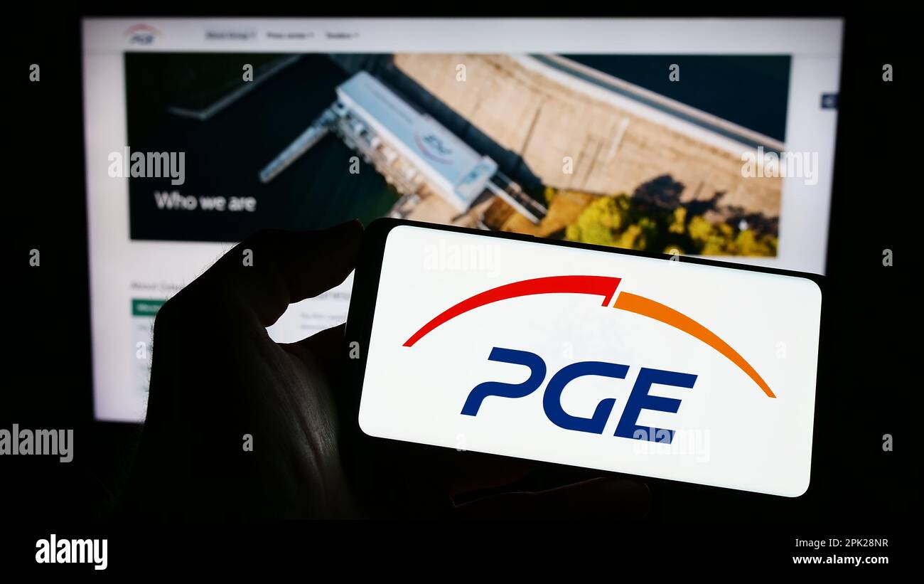 Person holding mobile phone with logo of company PGE Polska Grupa ...