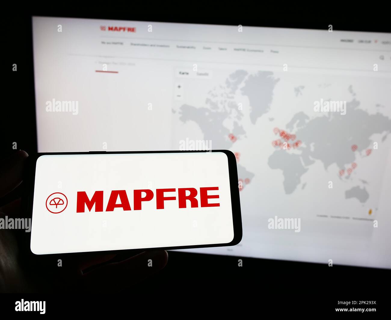 Person holding smartphone with logo of Spanish insurance company Mapfre ...