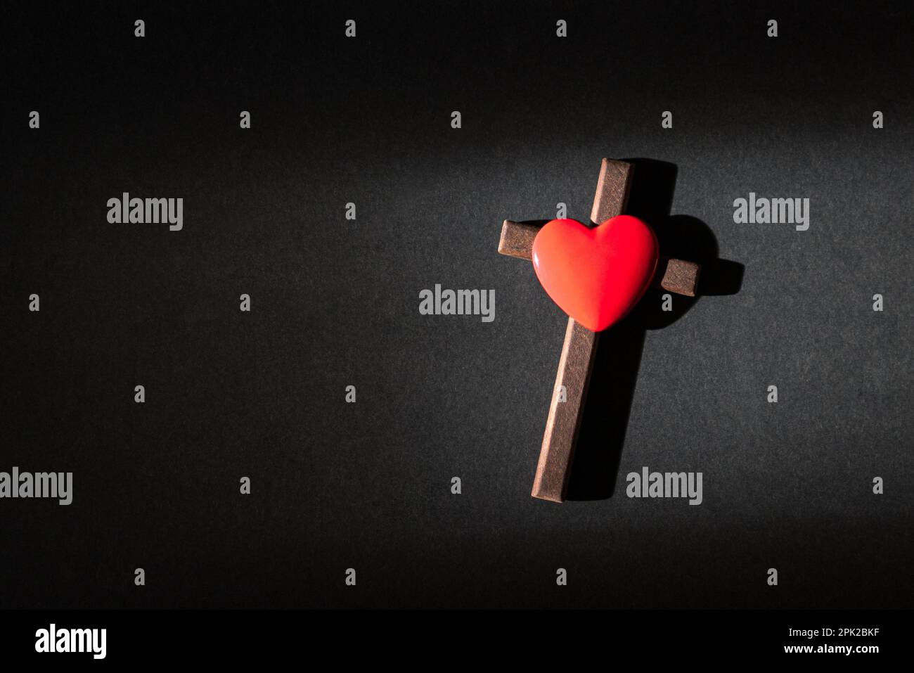 Red heart on top of wooden crucifix cross on black background. Top view ...