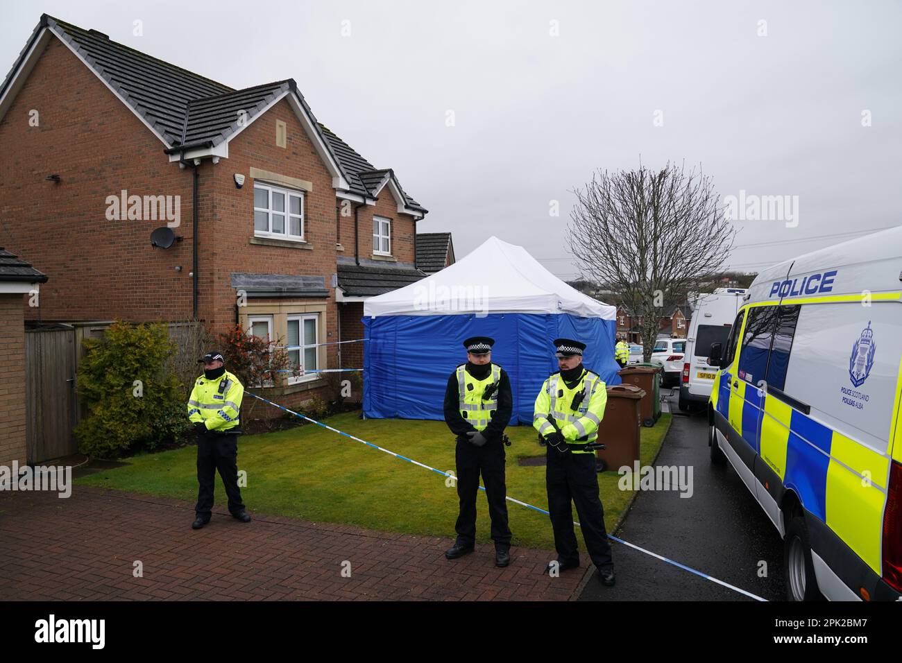 Officers from Police Scotland stand beside by police tape and a police ...