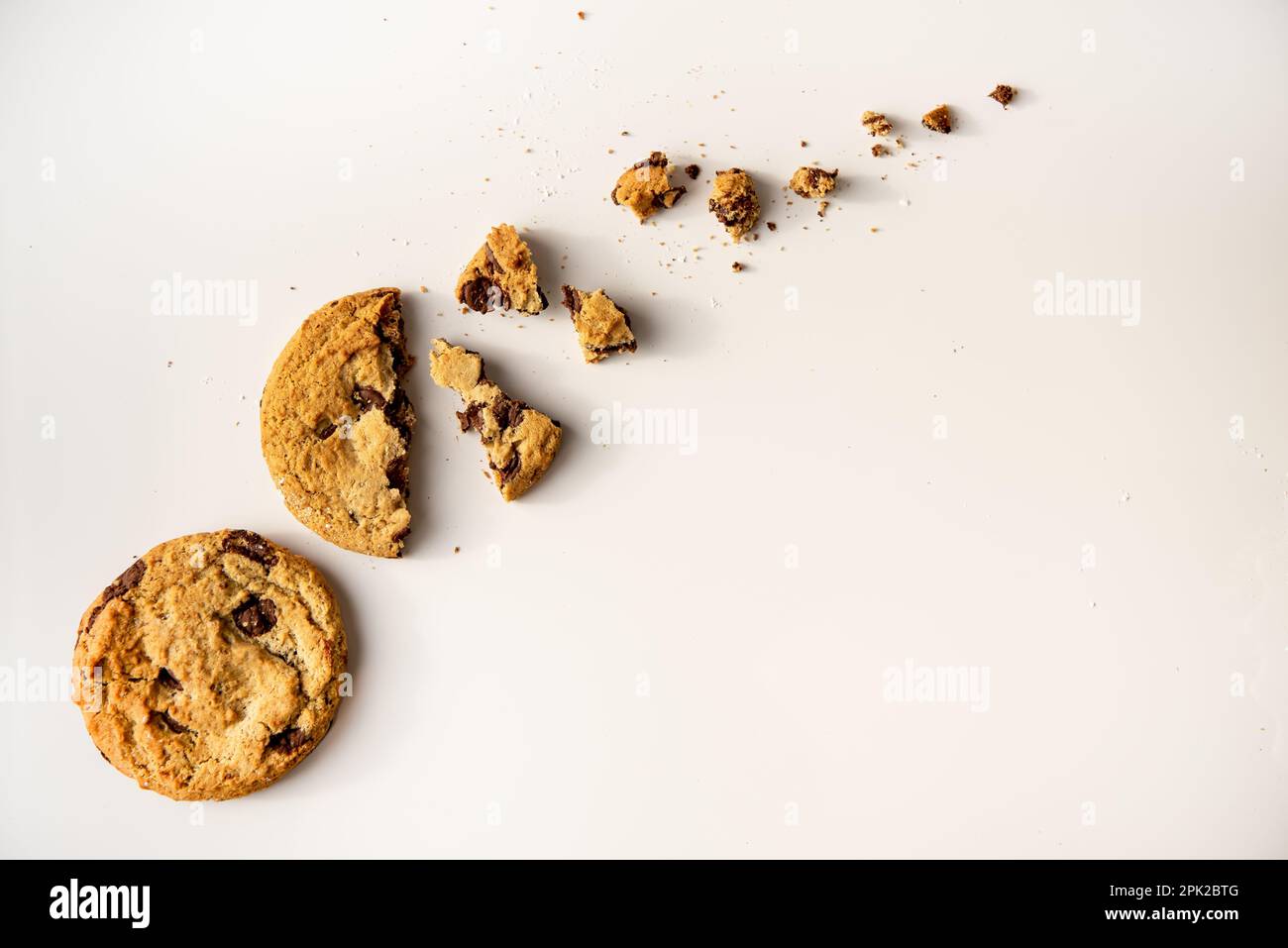 A chocolate chip cookie with broken pieces of the cookie, crumbled and ...