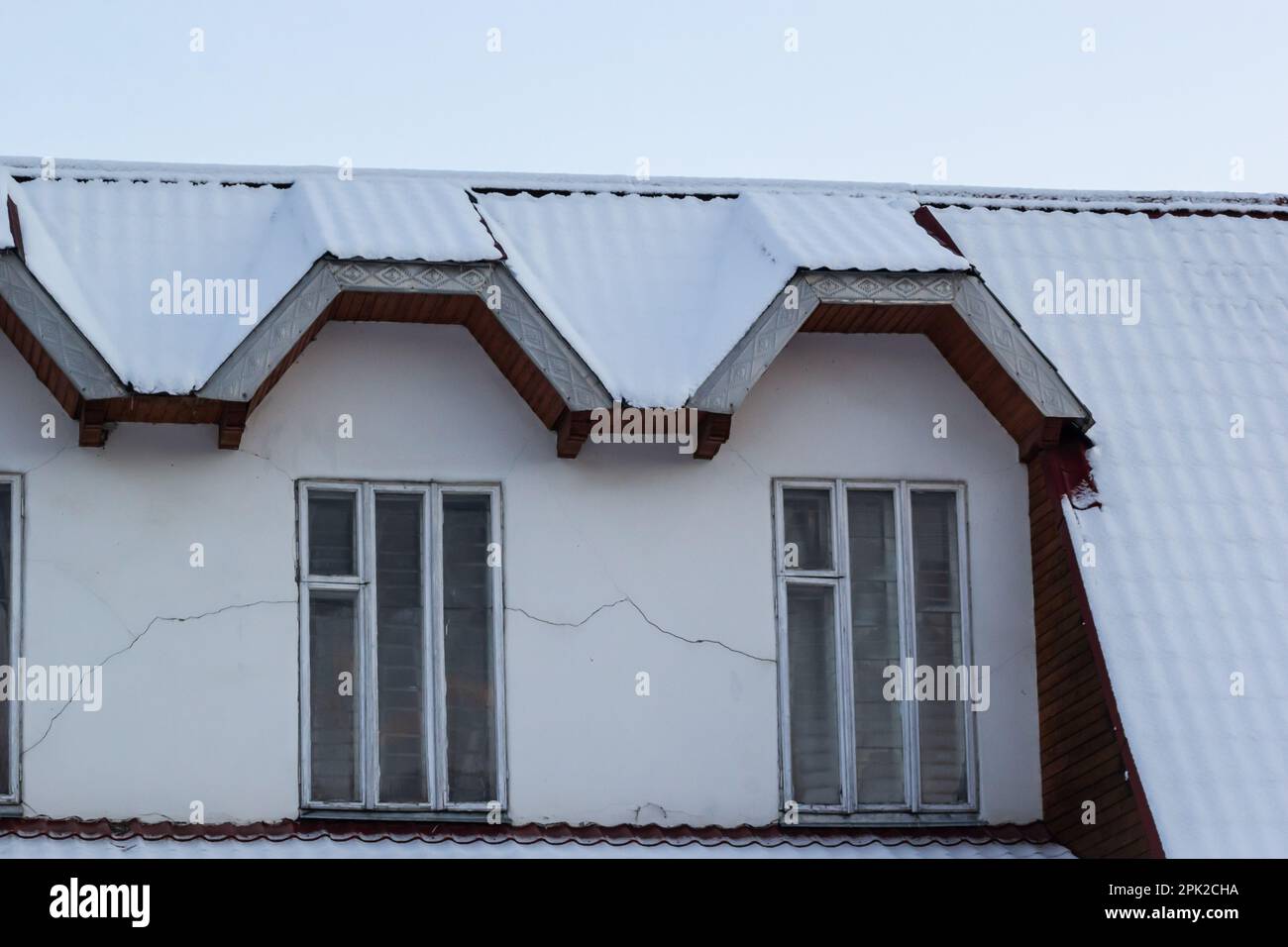 Snow on the roof of a red, brown metal roof of a European house with a ...