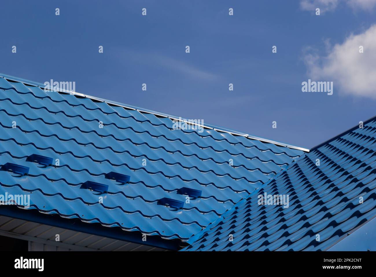 The roof of a house covered with sheets of blue metal tiles against the ...