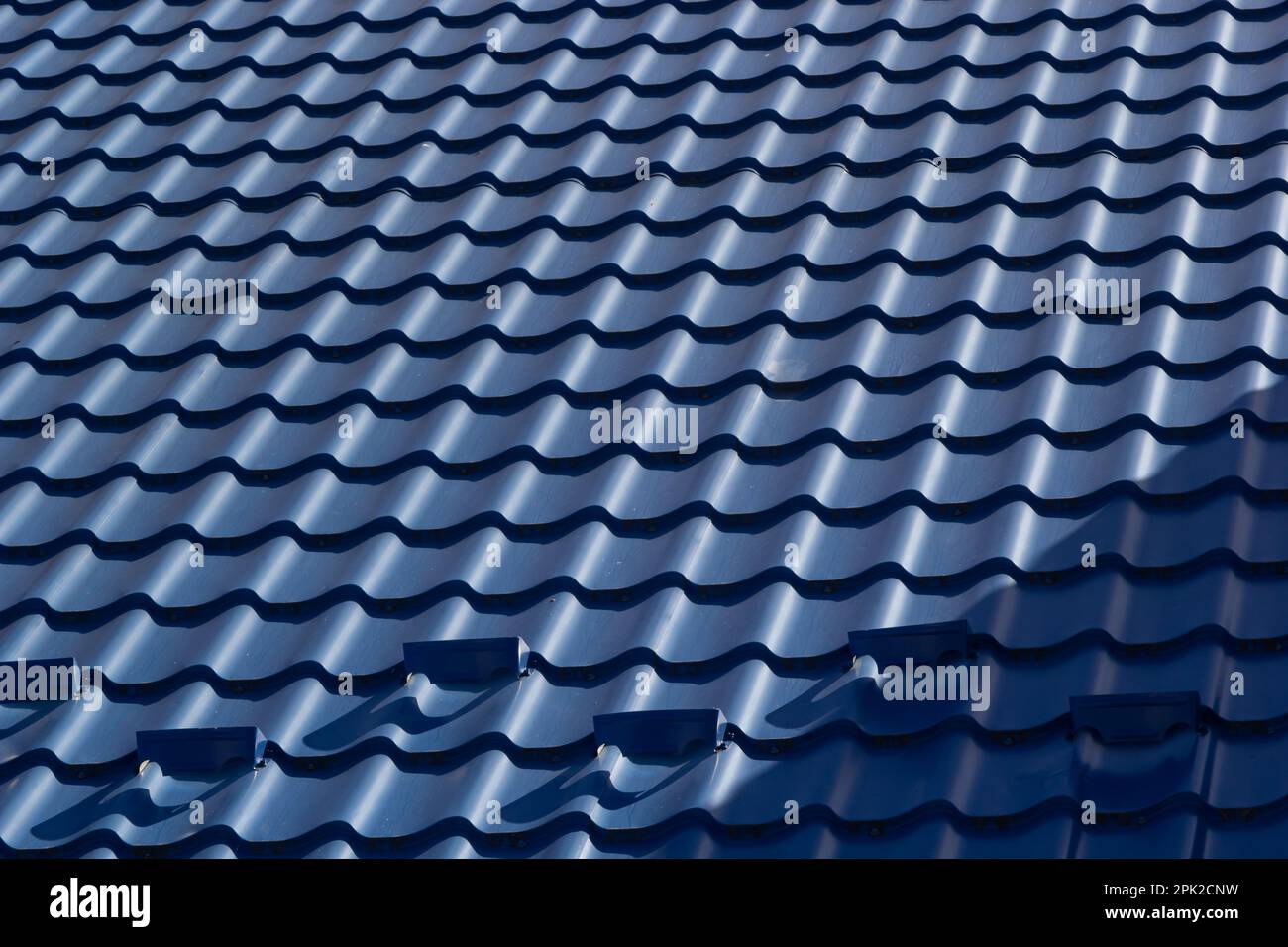 The roof of a house covered with sheets of blue metal tiles against the ...