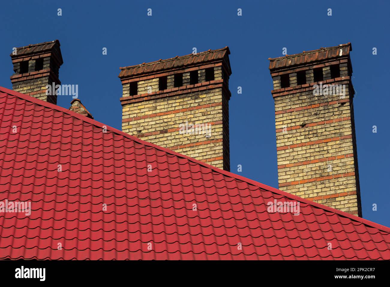 Red house roof with red brick chimney. Ceramic chimney, metal roof ...
