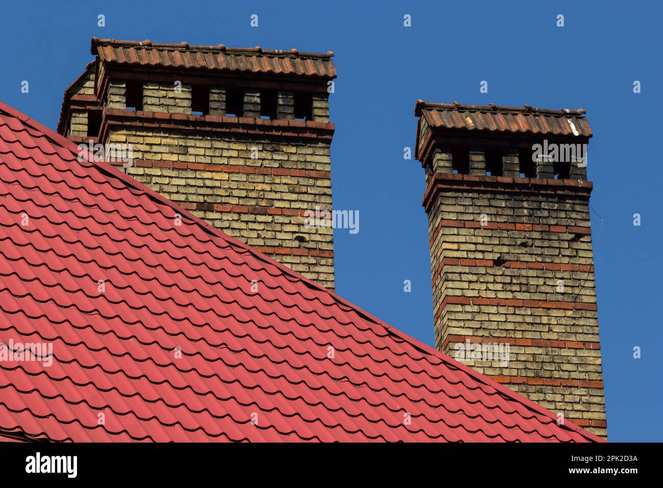 Red house roof with red brick chimney. Ceramic chimney, metal roof ...