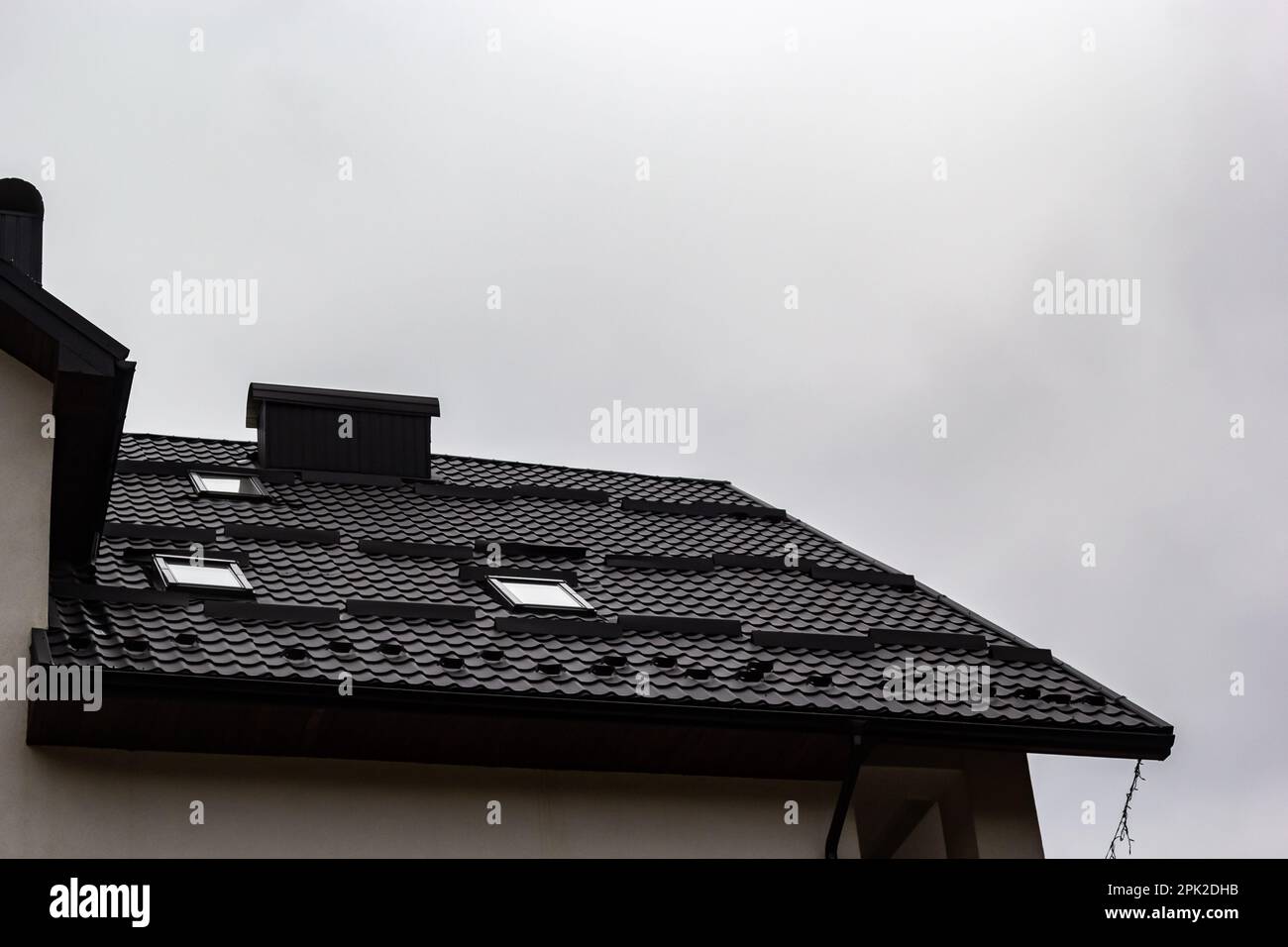 House with new brown metal tile roof and rain gutter. Metallic ...