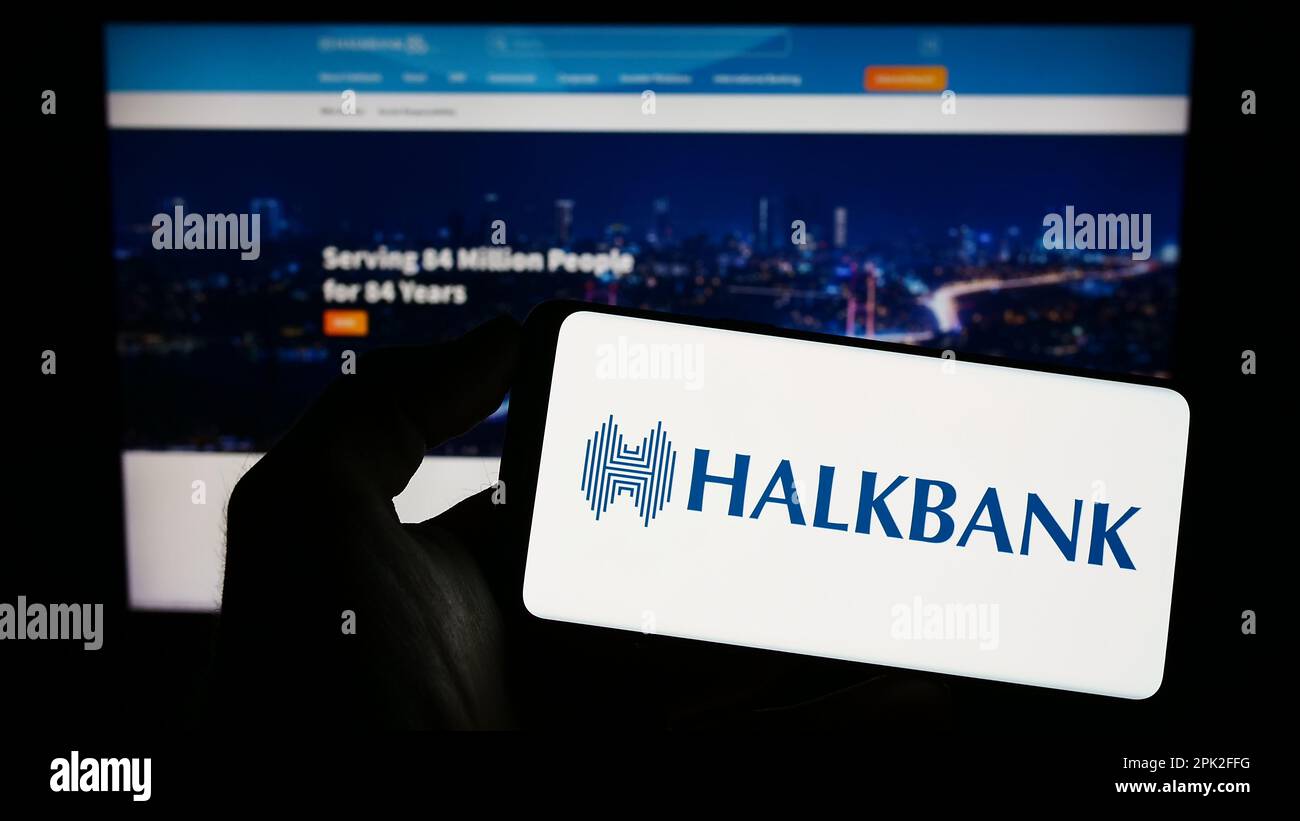 Person holding mobile phone with logo of company Turkiye Halk Bankasi A.S. (Halkbank) on screen ...