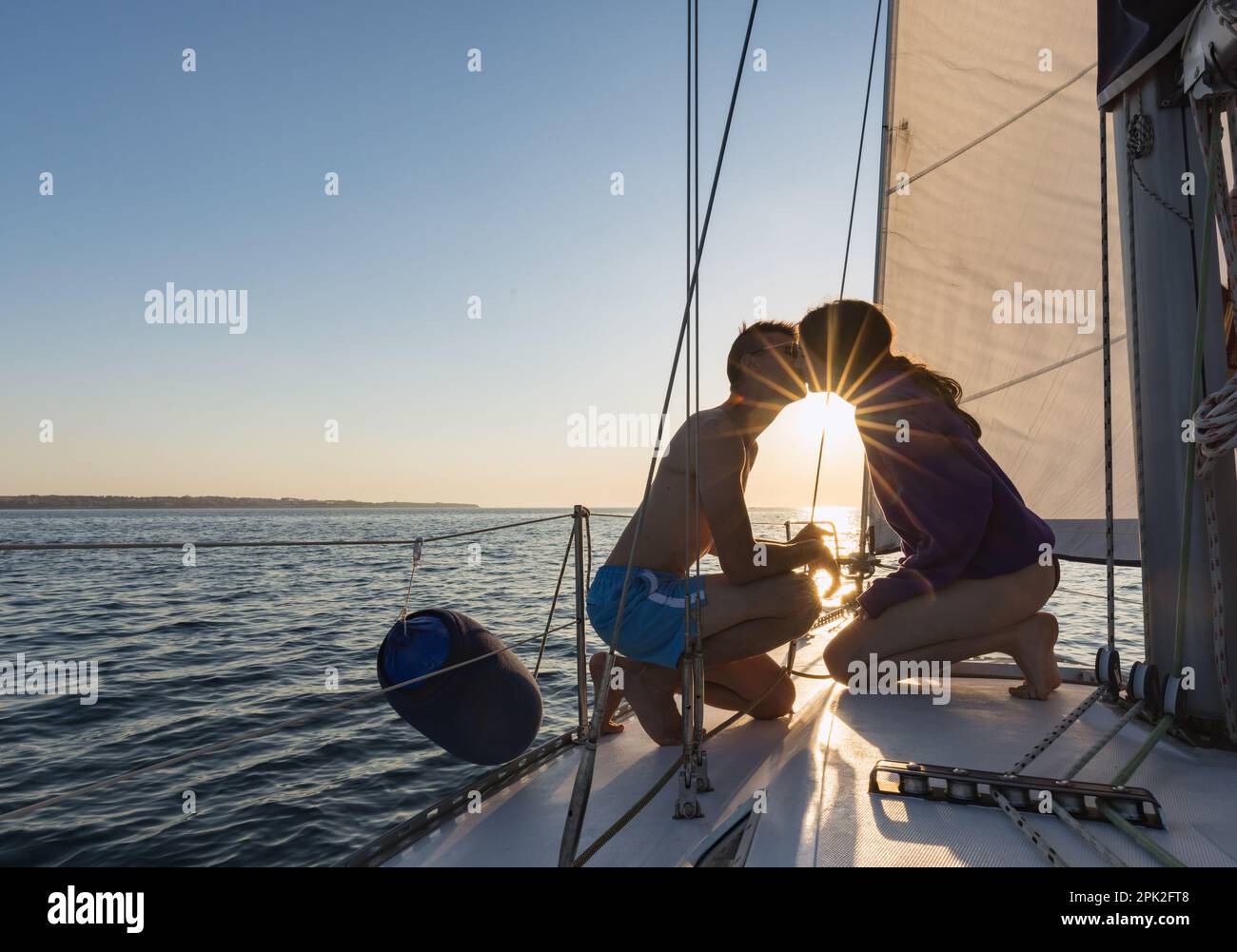 Couple kissing on a sailboat yacht sailing in the sea at colorful ...
