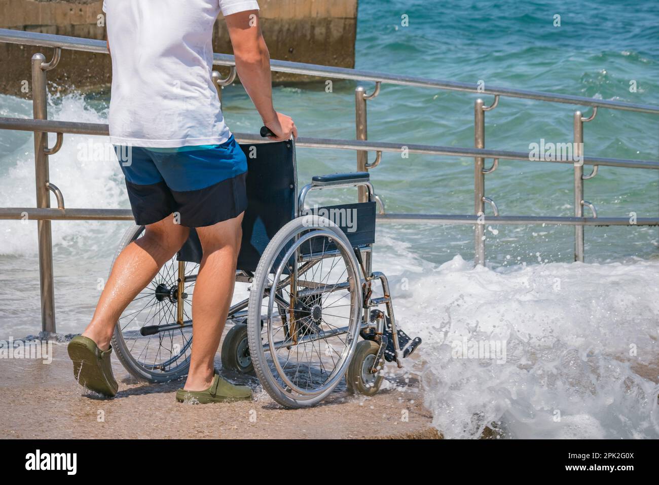 Lifeguard pushing wheelchair at sea on accessible beach with ramp for ...