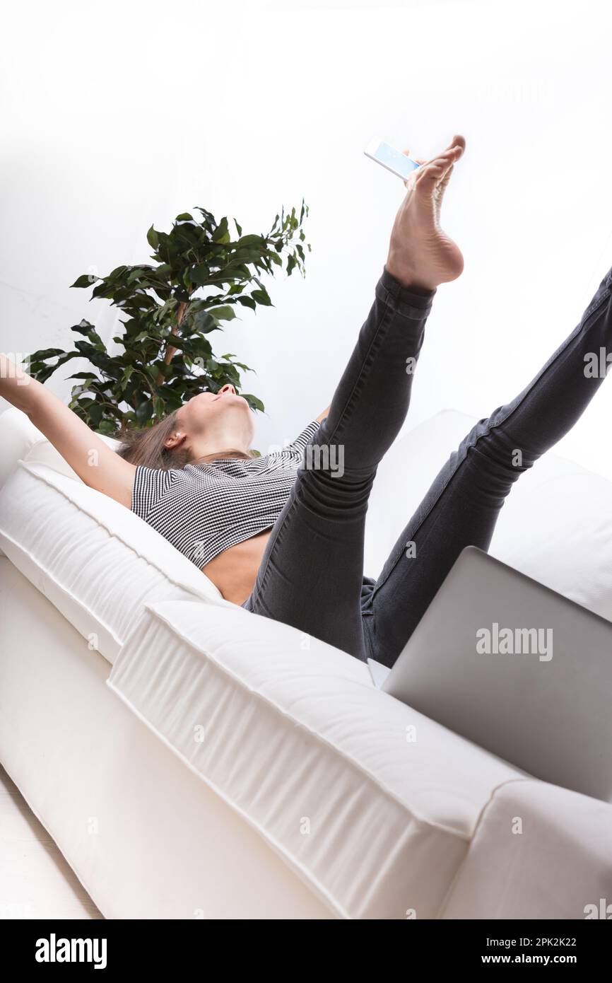 Young woman or girl takes a selfie while lying on her back on her white ...