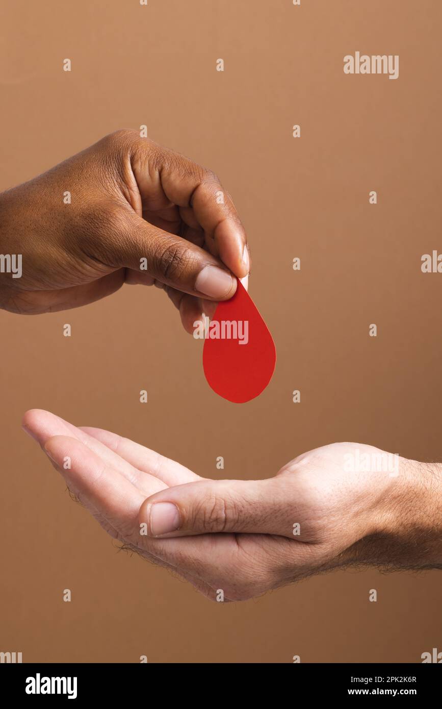 Hands of biracial man giving blood drop to caucasian man, on brown ...