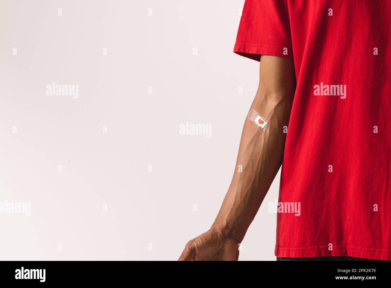 Midsection of biracial man with heart sticking plaster on arm, on white ...