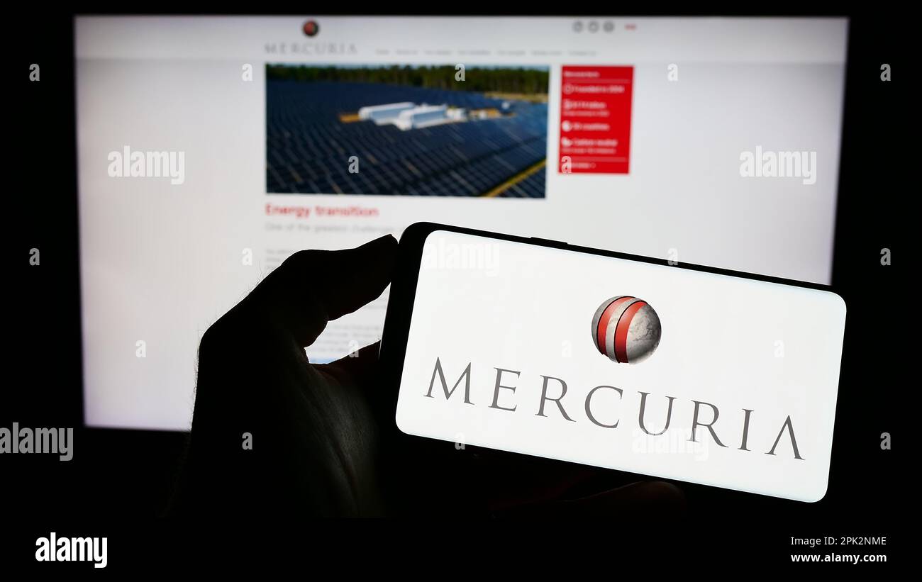 Person holding mobile phone with logo of commodity trading company ...