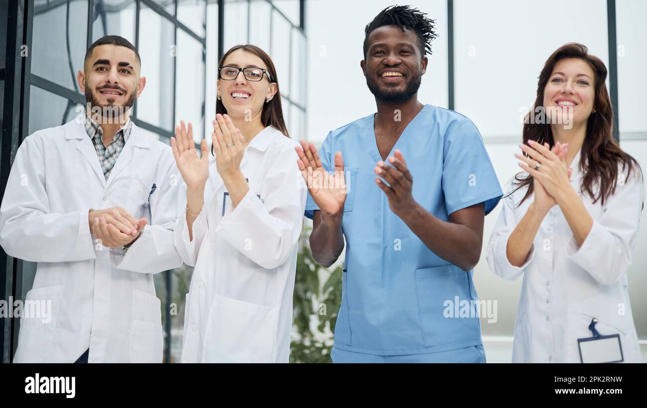 Successful team of different doctors clapping hands Stock Photo - Alamy