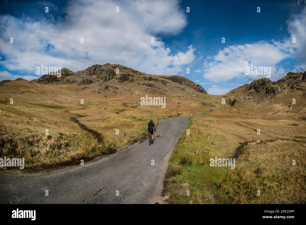 Road cyclist climbing Hardknott Pass on a quiet afternoon in May ...