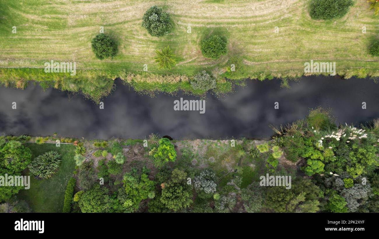 Aerial view of a green grassy meadow with a small stream flowing ...