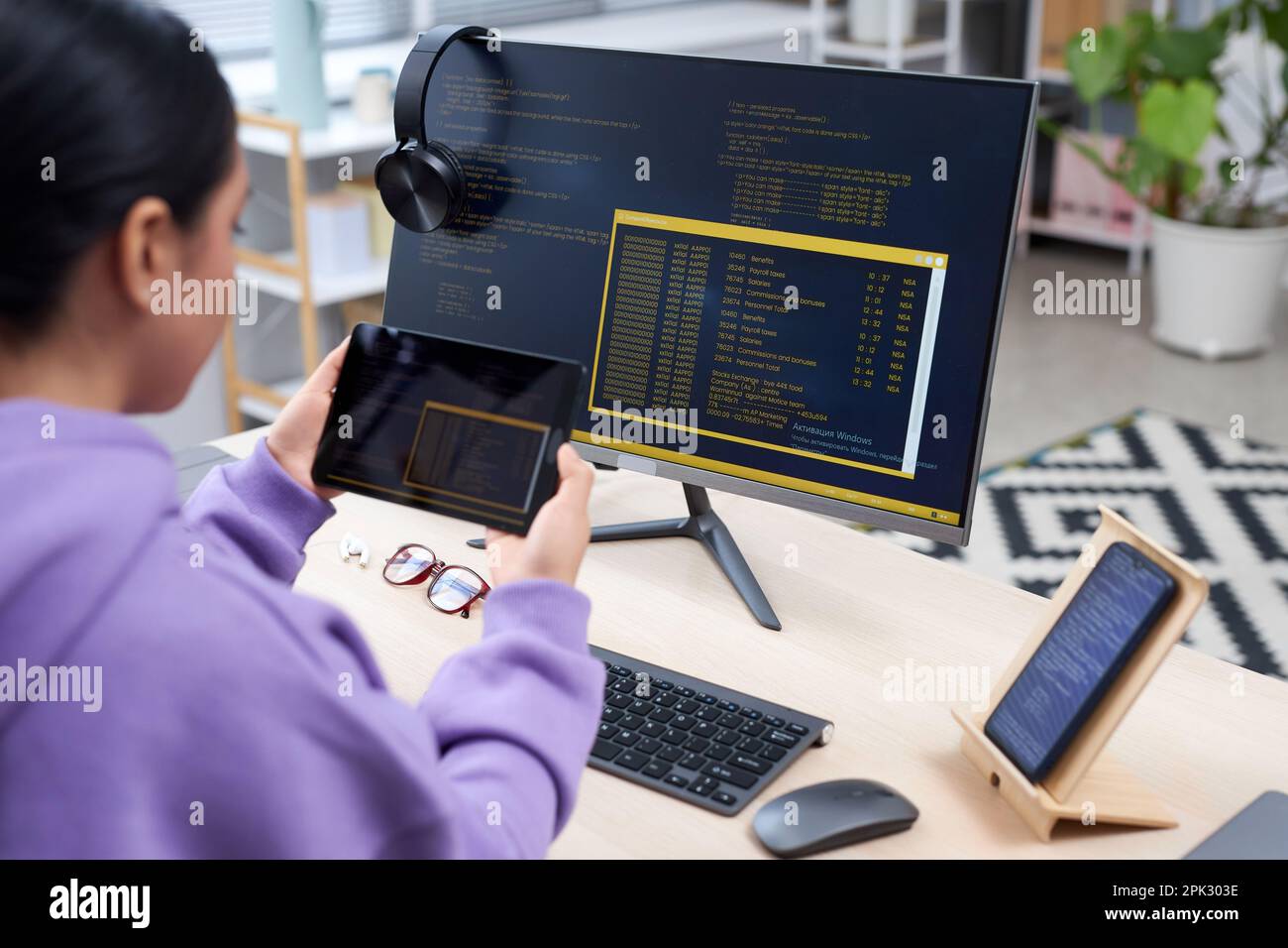 Side view of female IT programmer holding tablet and writing code for ...