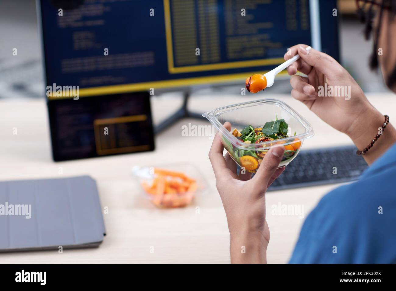 Closeup of unrecognizable man eating takeout lunch at workplace while ...