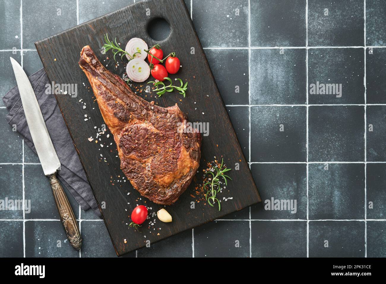 Tomahawk steak. Sliced grilled tomahawk beef steak with baked cherry ...