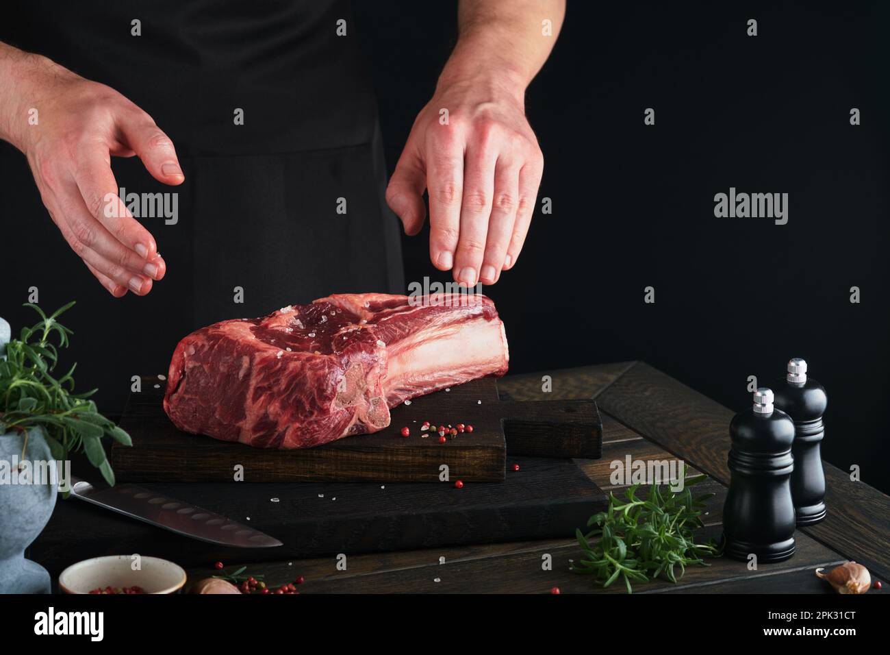Chef cutting steak beef. Mans hands hold raw steak Tomahawk on rustic ...