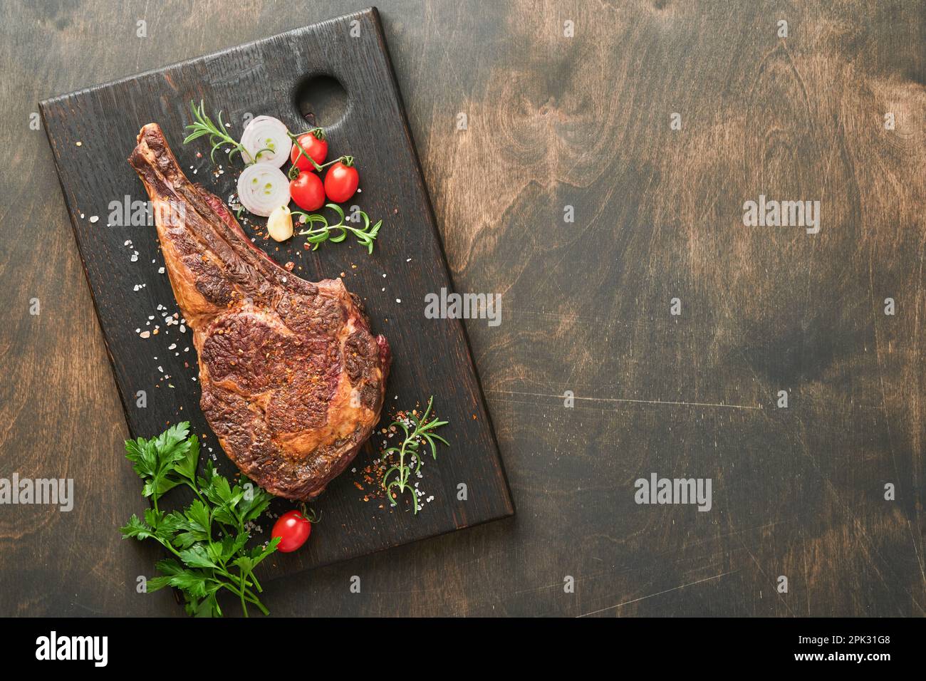 Tomahawk steak. Sliced grilled tomahawk beef steak with baked cherry ...