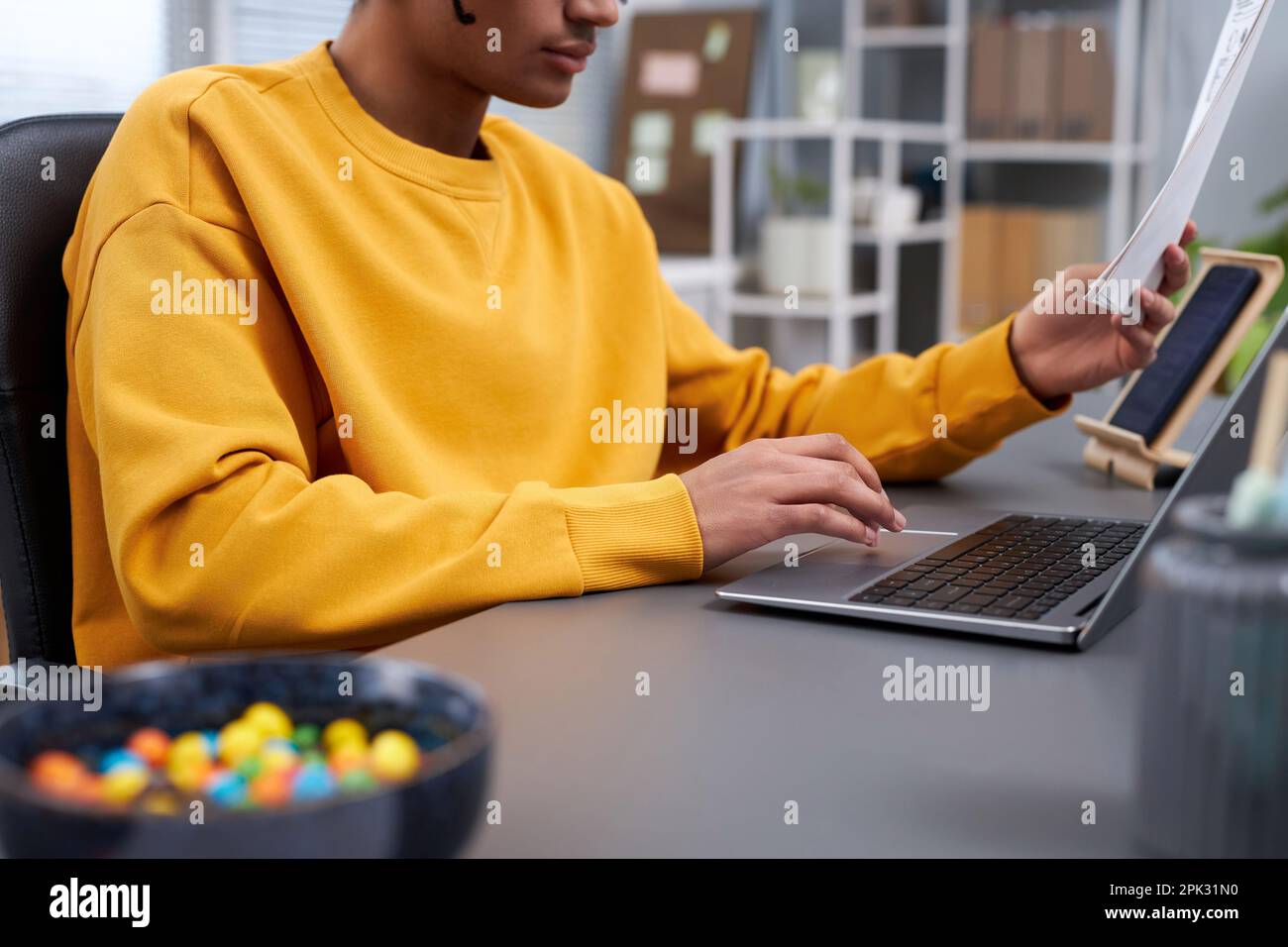 Side view closeup of young black man working or studying at home office ...