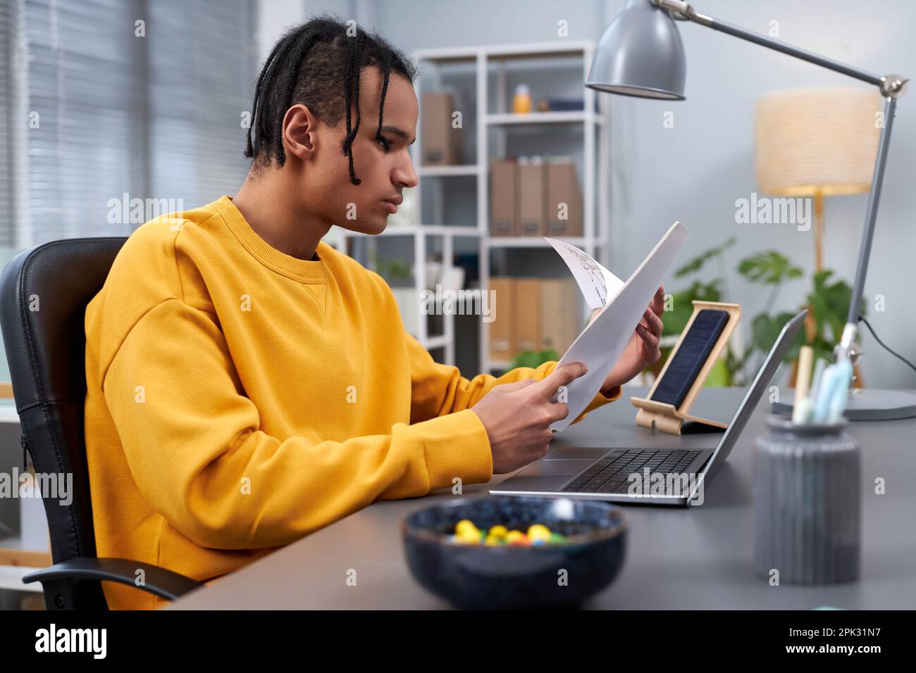 Side view portrait of young black man working or studying at home ...