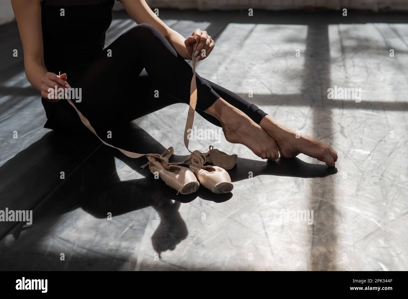 Faceless ballerina sits on the floor and puts on pointe shoes Stock ...