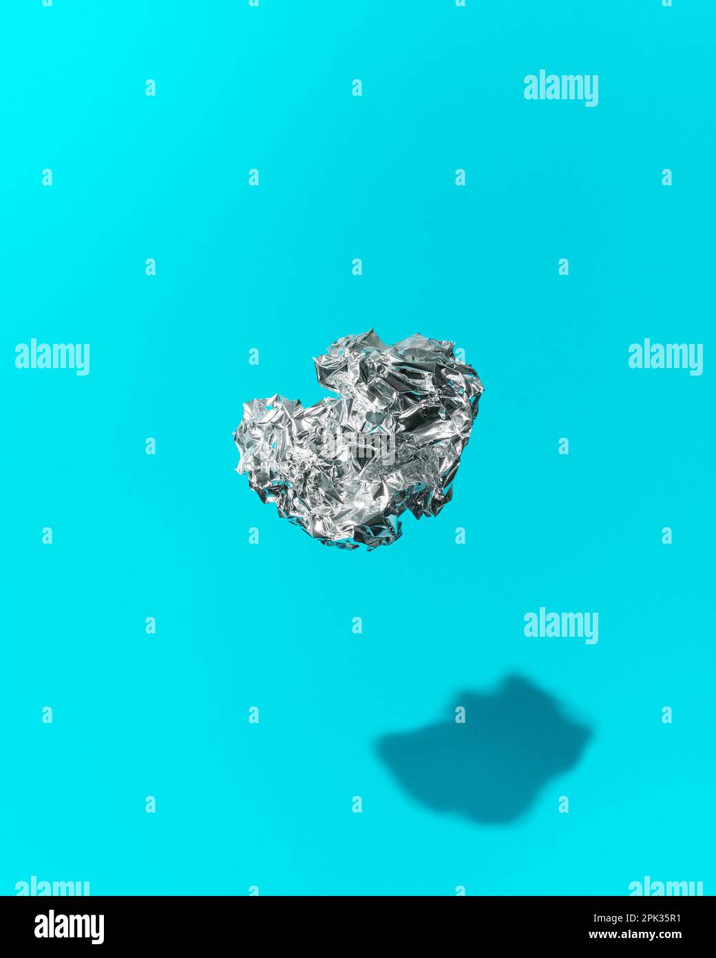 Ball of Crumpled Aluminum Foil Floating Mid-Air on a Blue Background ...