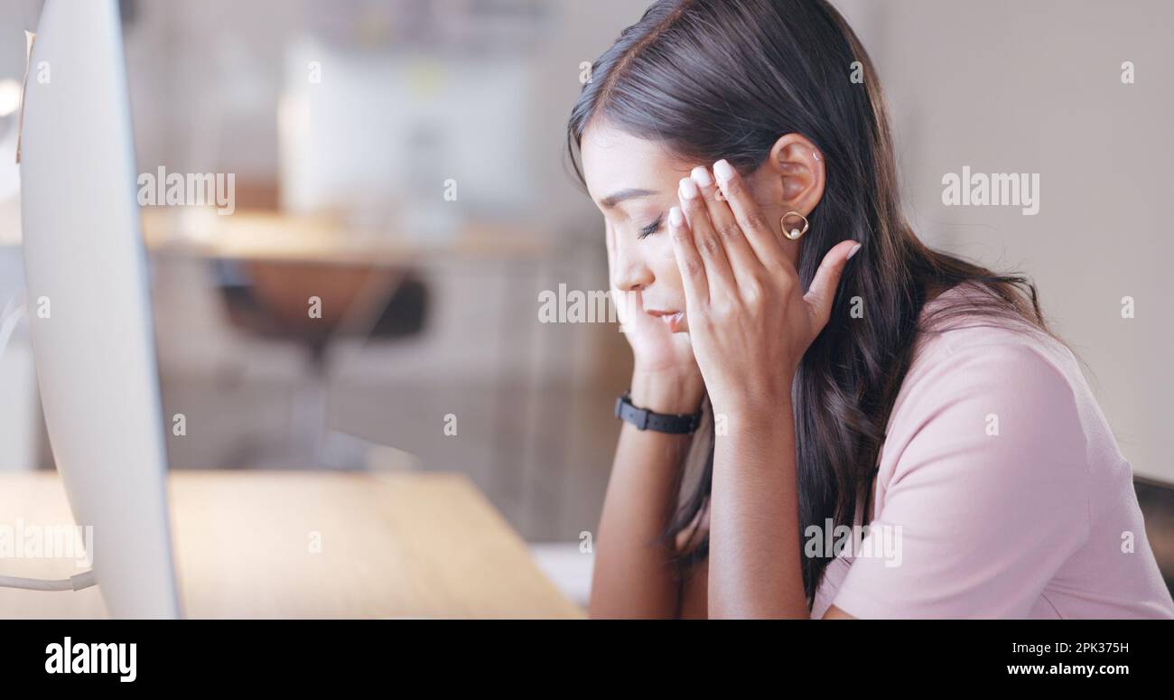Woman suffering from a headache or migraine while working on desktop ...