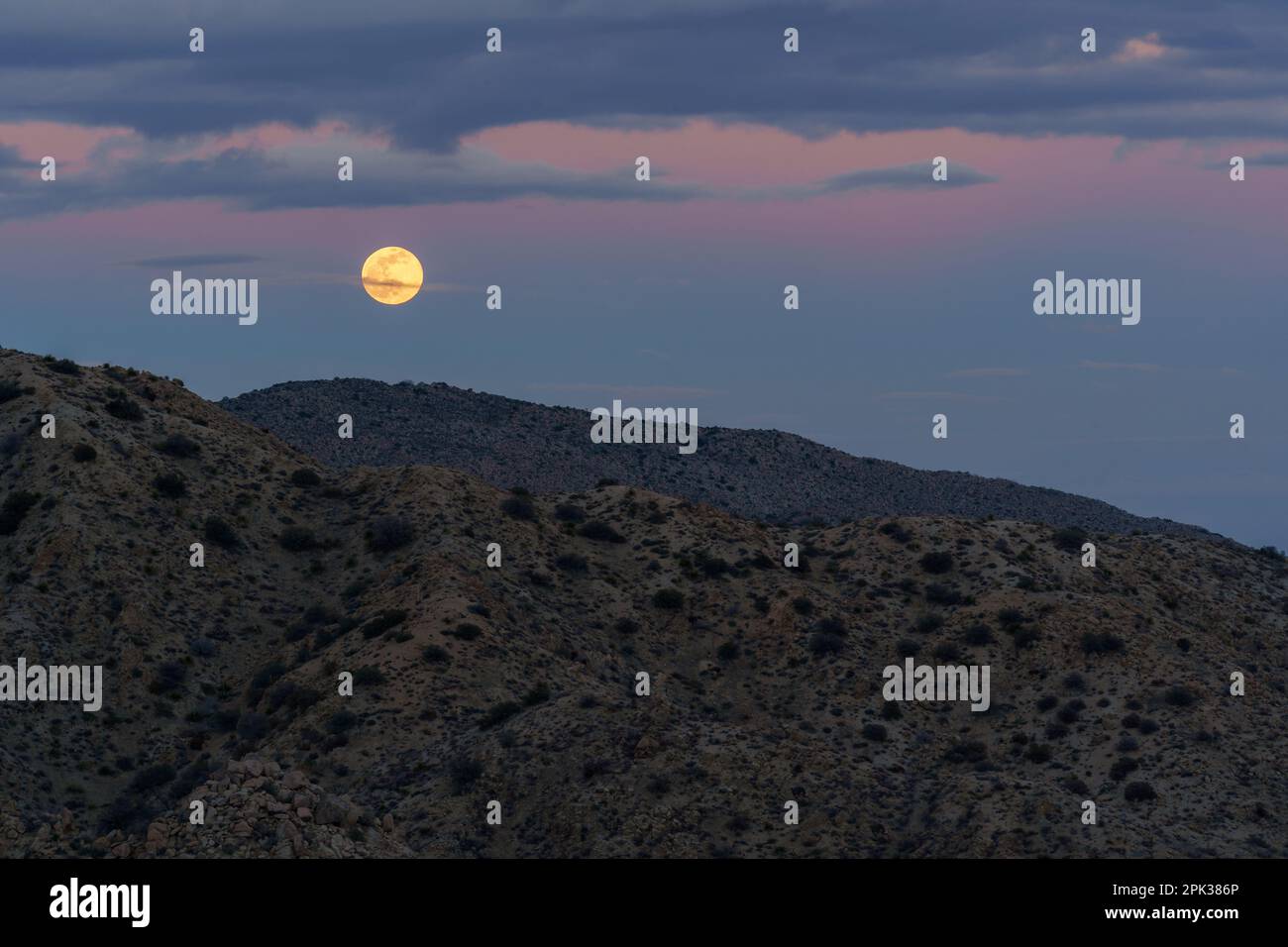 Full Wolf Moon Rising with a Cloudy Pastel Sky Over Desert Mountain ...