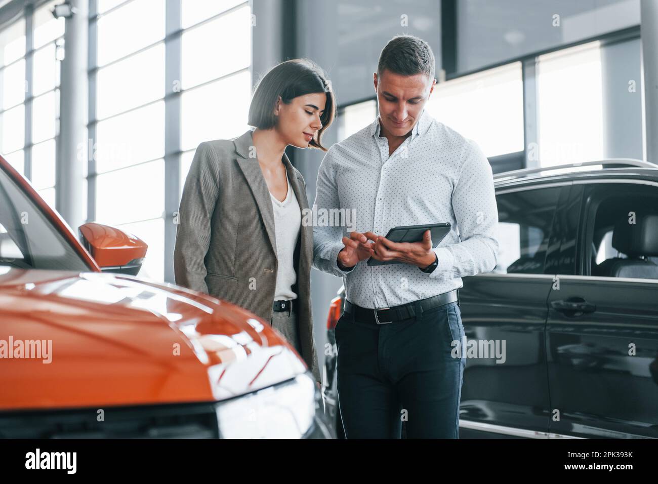 Talking with each other. Man in formal wear helping customer with ...