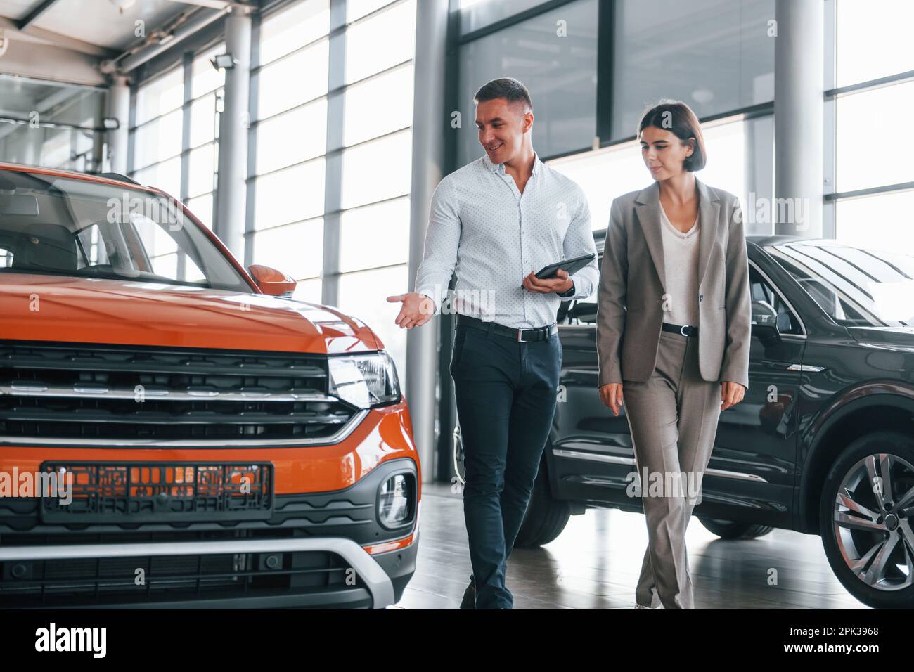 Modern vehicle. Man in formal wear helping customer with choice of the ...
