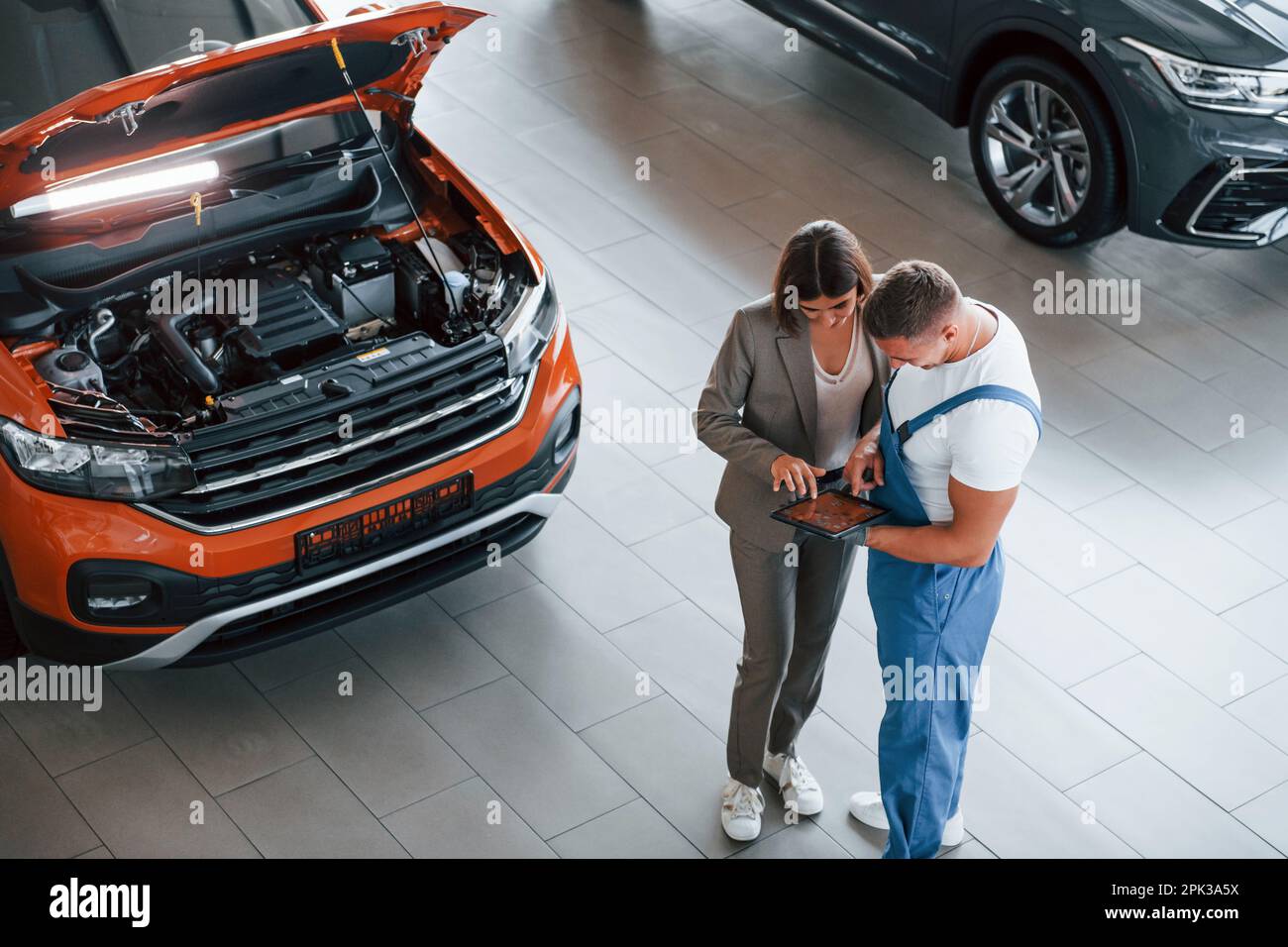 Two people. Man repairing woman's automobile indoors. Professional ...