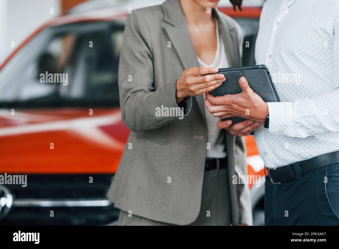 Modern vehicles. Man in formal wear helping customer with choice of the ...