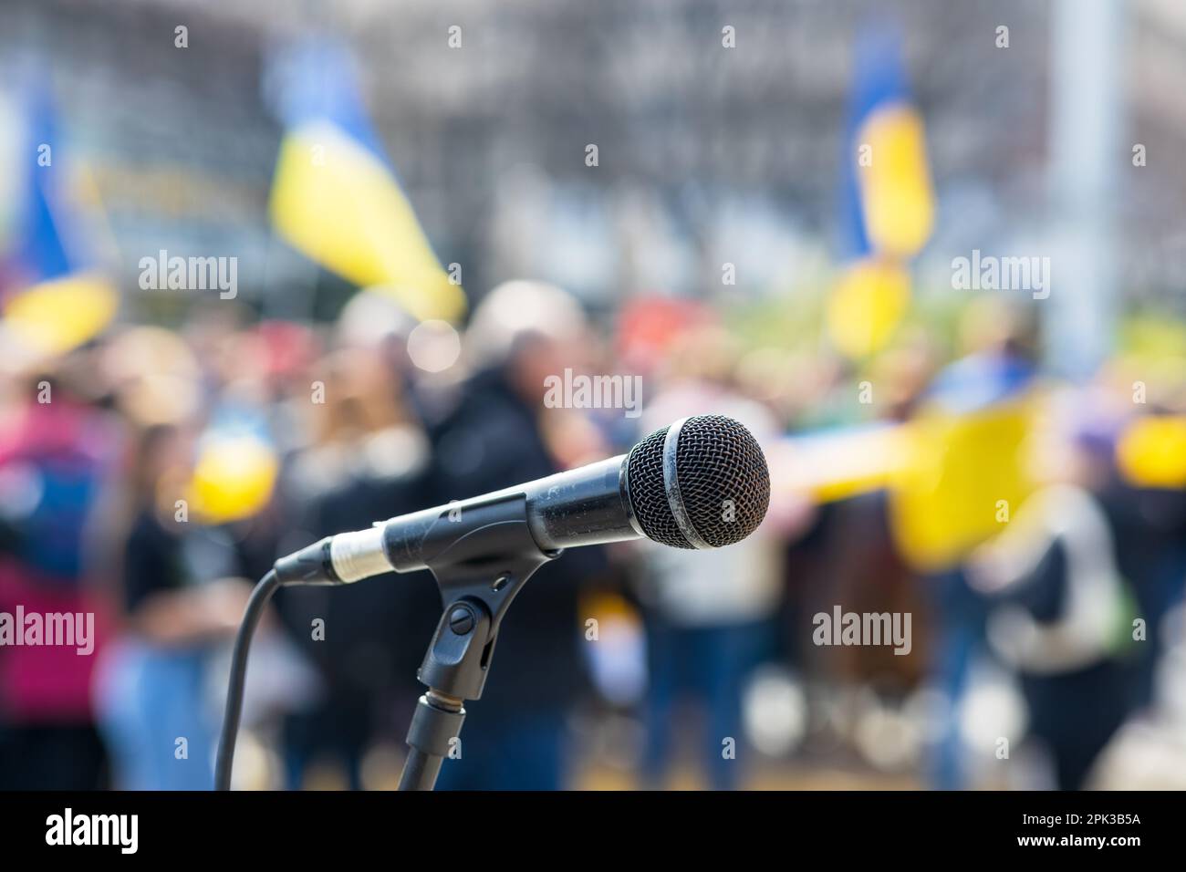 Anti-war protest, focus on microphone, blurred crowd of people with ...