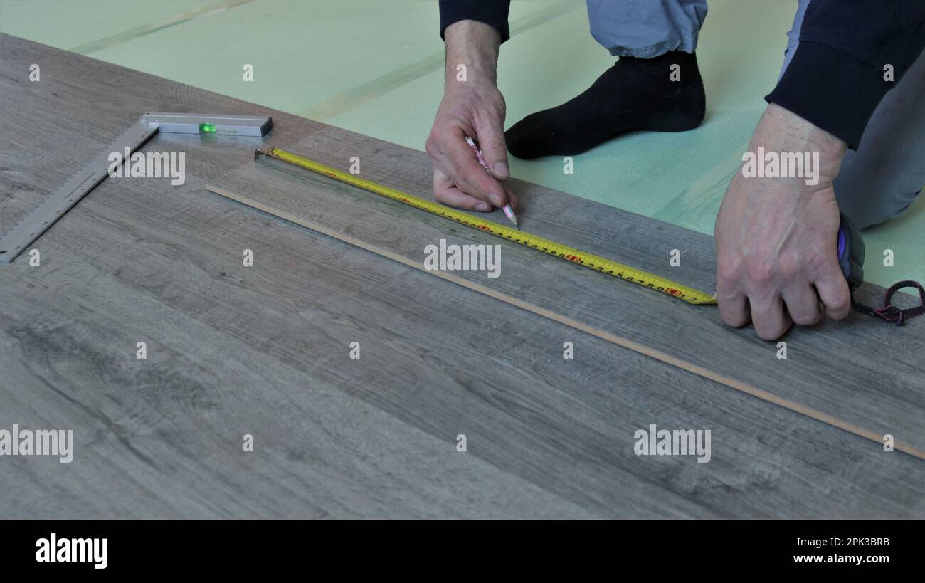 measuring a laminate board with a tape measure in the hands of a worker ...