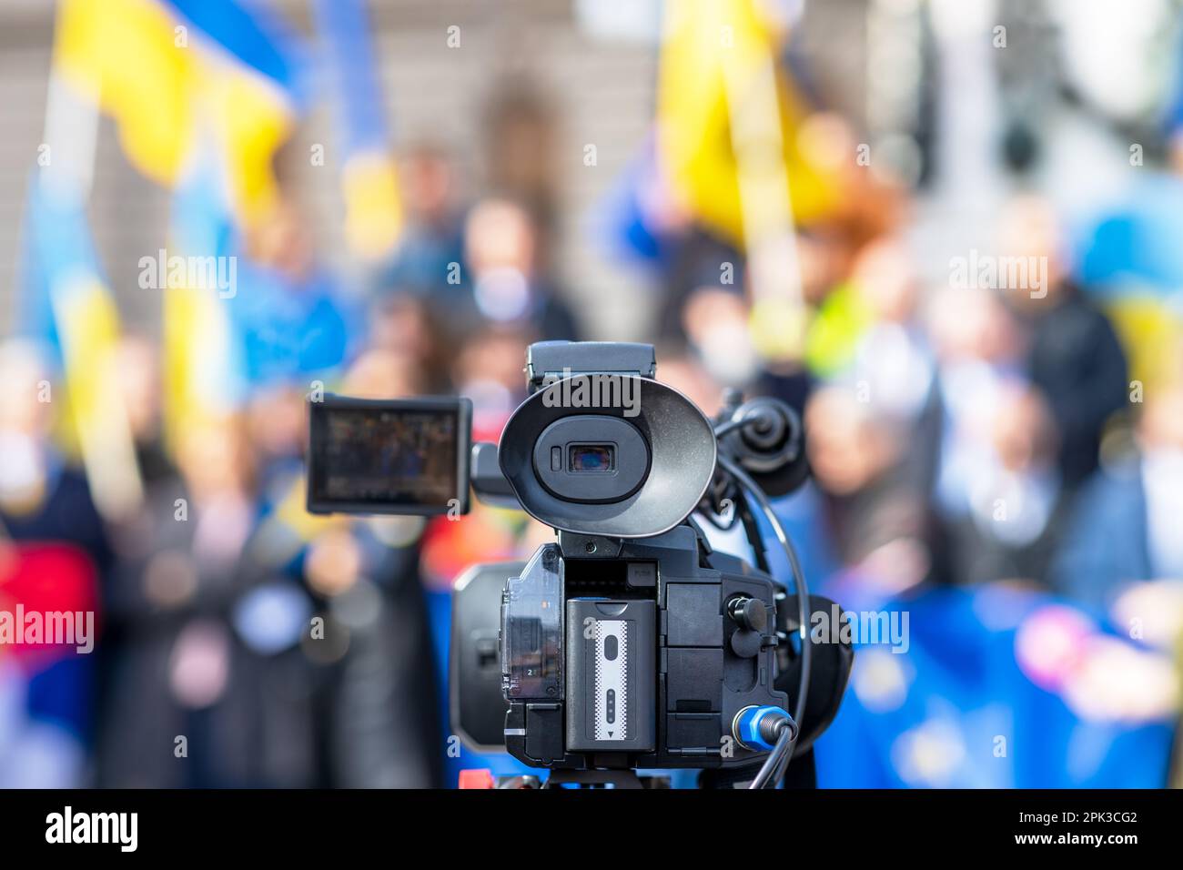 Anti-war meeting, focus on video camera, blurred crowd of people with ...