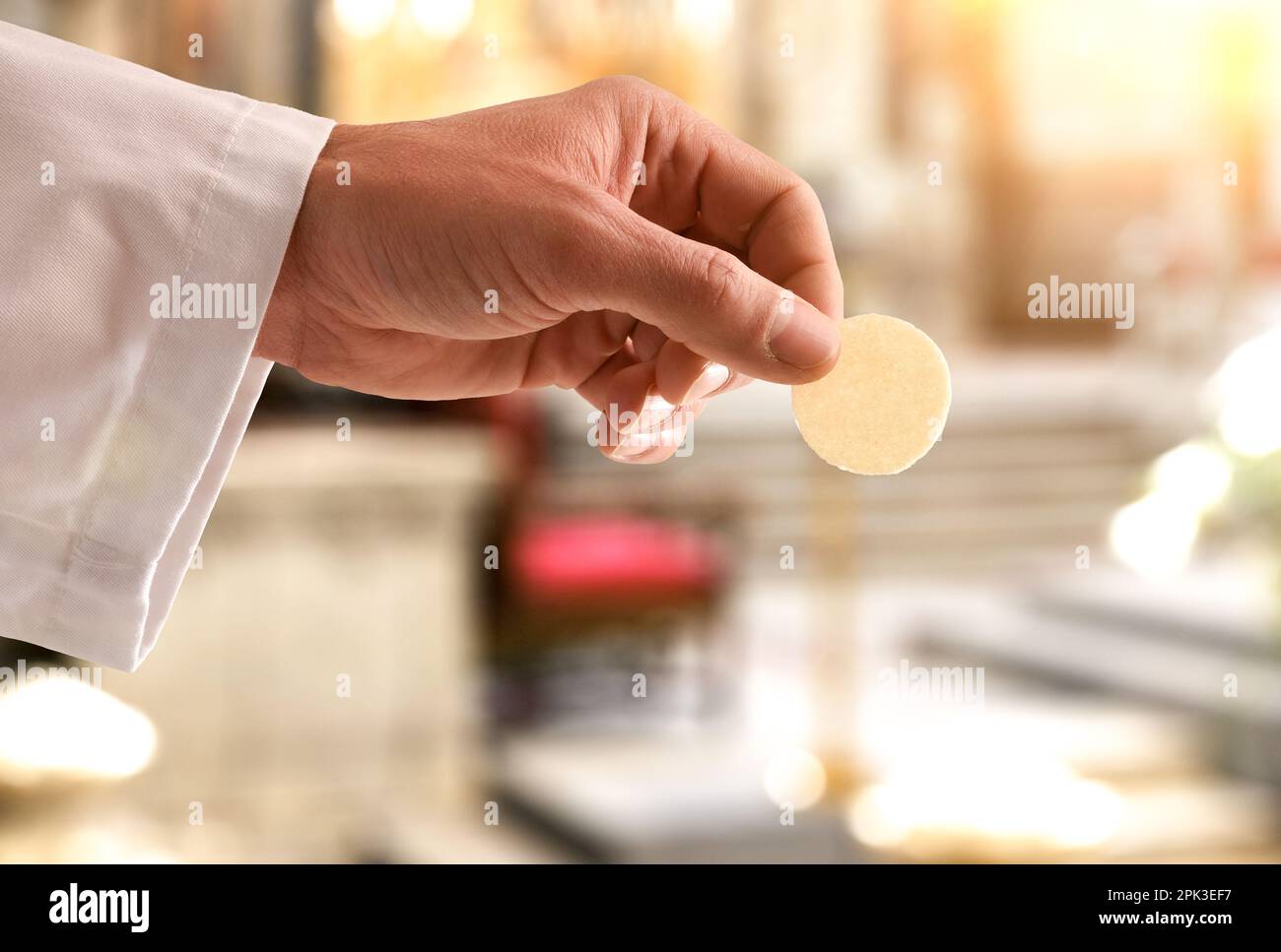 Detail of the hand of a priest giving a consecrated host for communion ...
